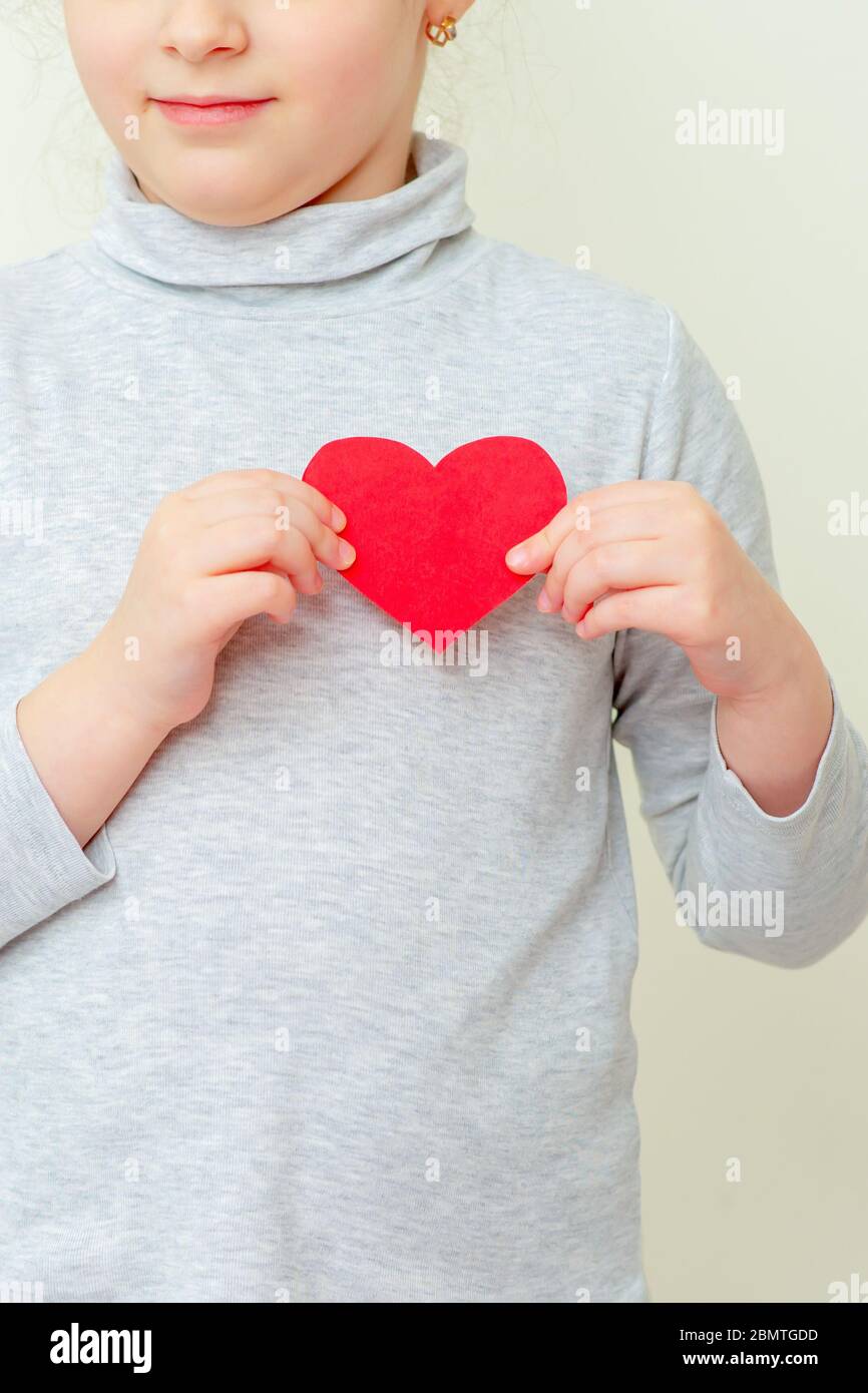 Red heart in hands of little girl on white background. Child is holding ...