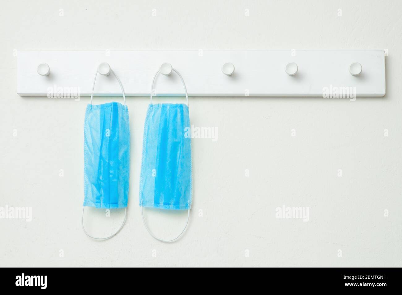 Protective medical masks hanging on hooks of wooden white hanger on a ...