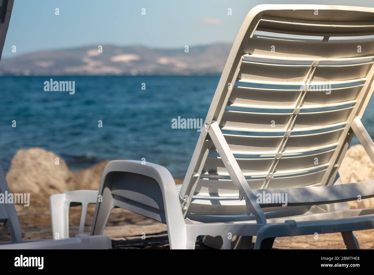 View of a plastic white foldable beach bed near the long beautiful blue ...