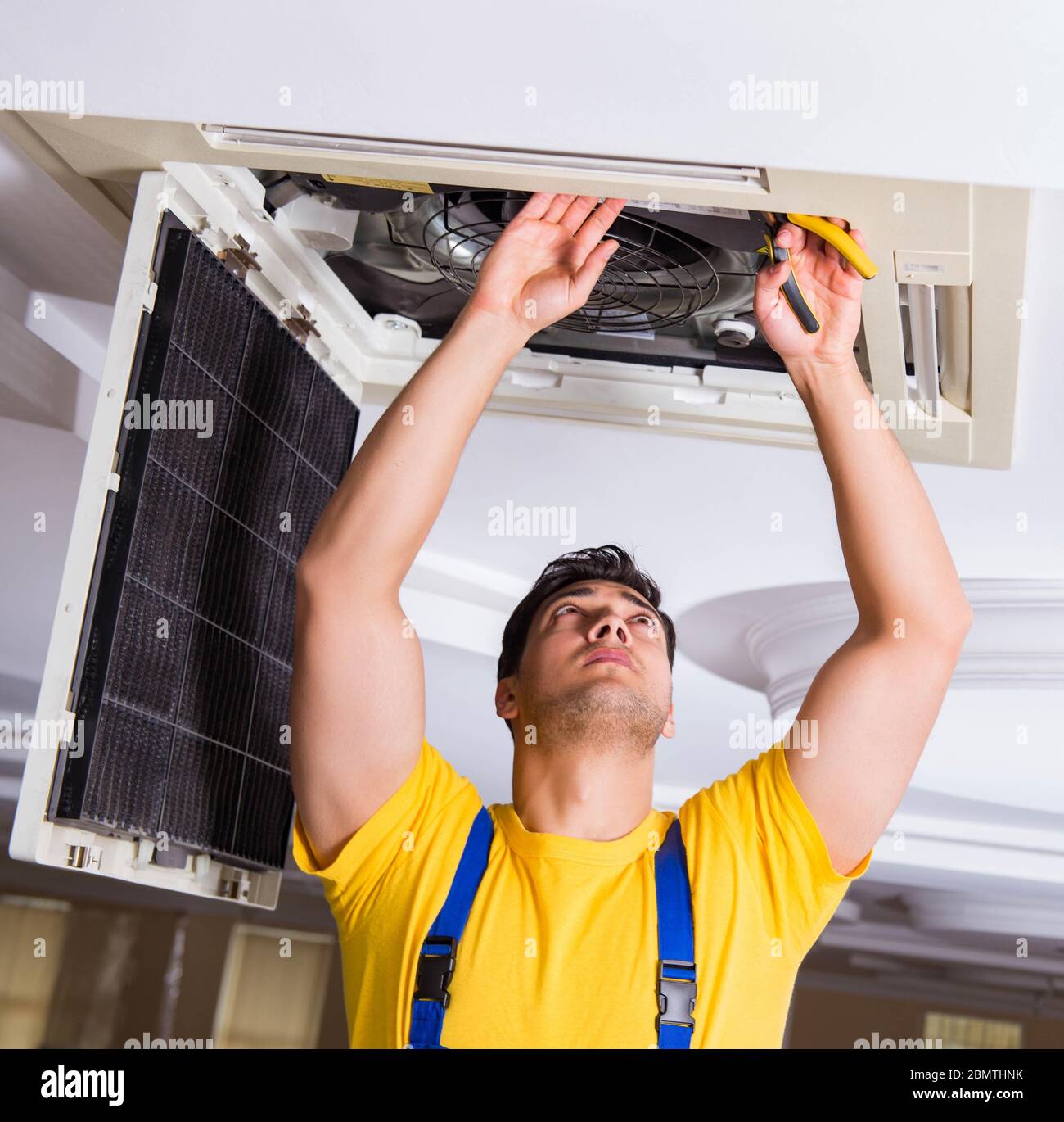 The repairman repairing ceiling air conditioning unit Stock Photo - Alamy