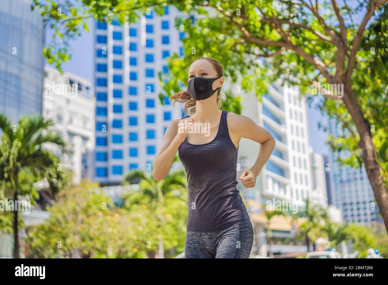 Woman runner wearing medical mask. Running in the city against the ...