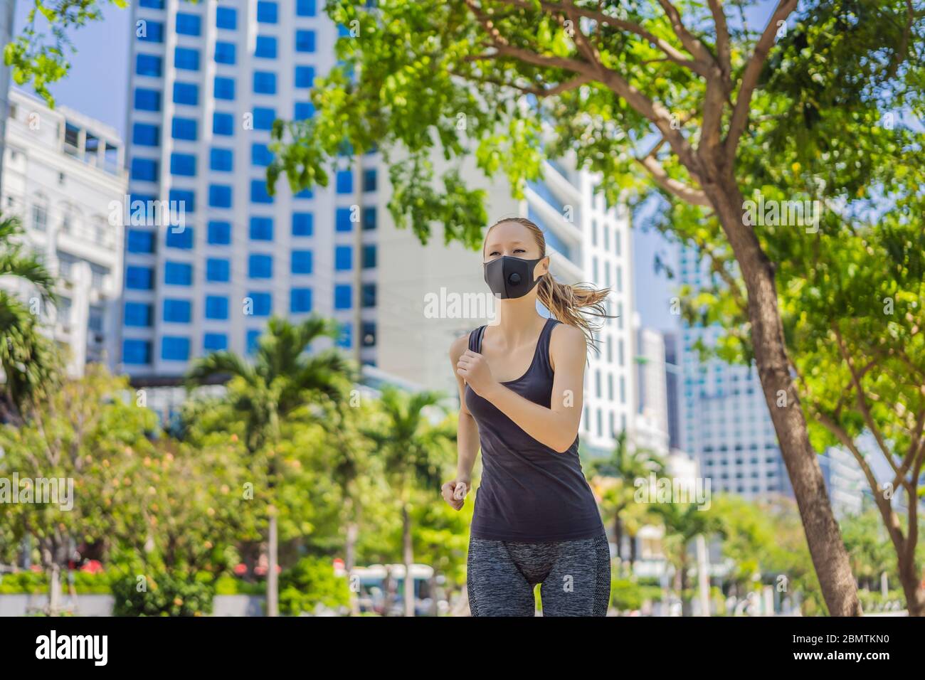 Woman runner wearing medical mask. Running in the city against the ...
