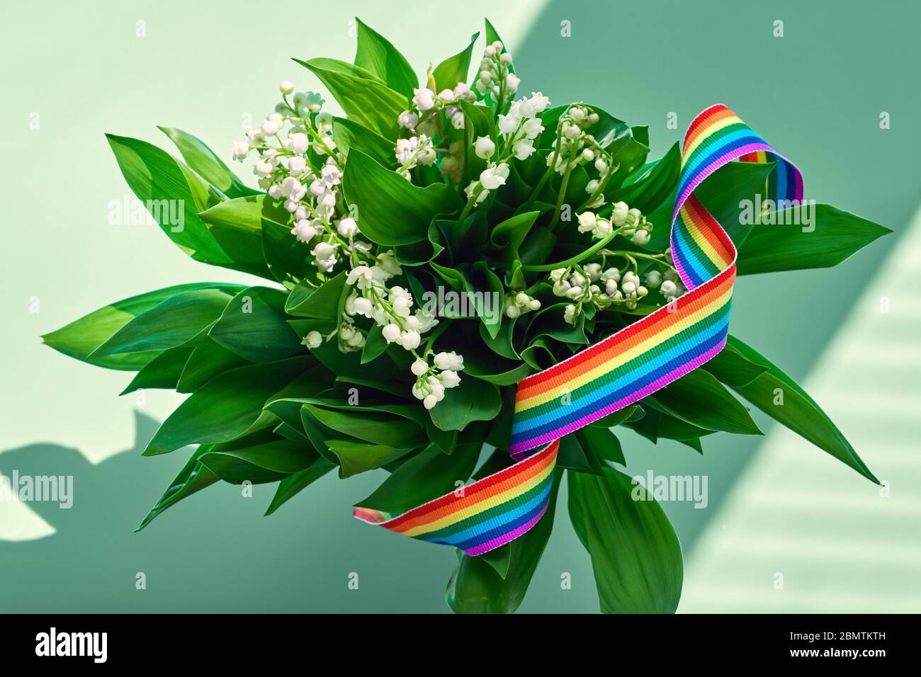 Bunch of fresh cup flowers, lily of the valley, with rainbow ribbon ...
