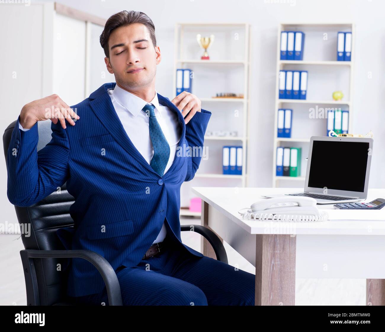 The young businessman doing sports stretching at workplace Stock Photo ...