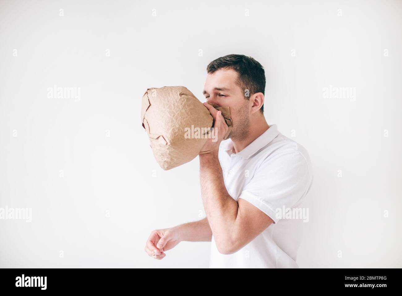 Young sick man isolated over white background. Guy vomiting into bag ...