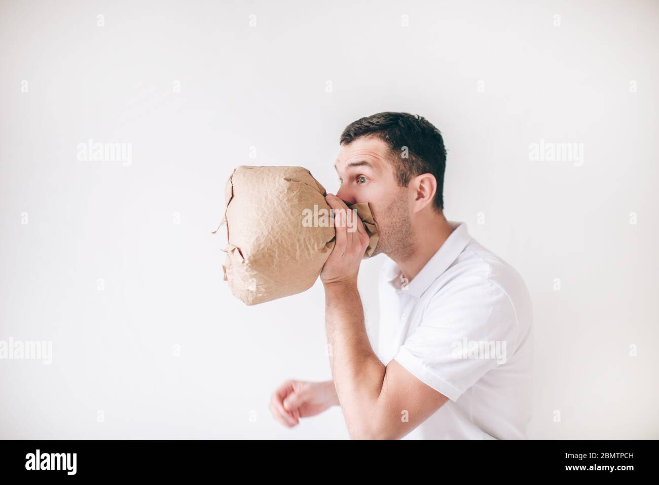 Young sick man isolated over white background. Guy vomining into bag ...