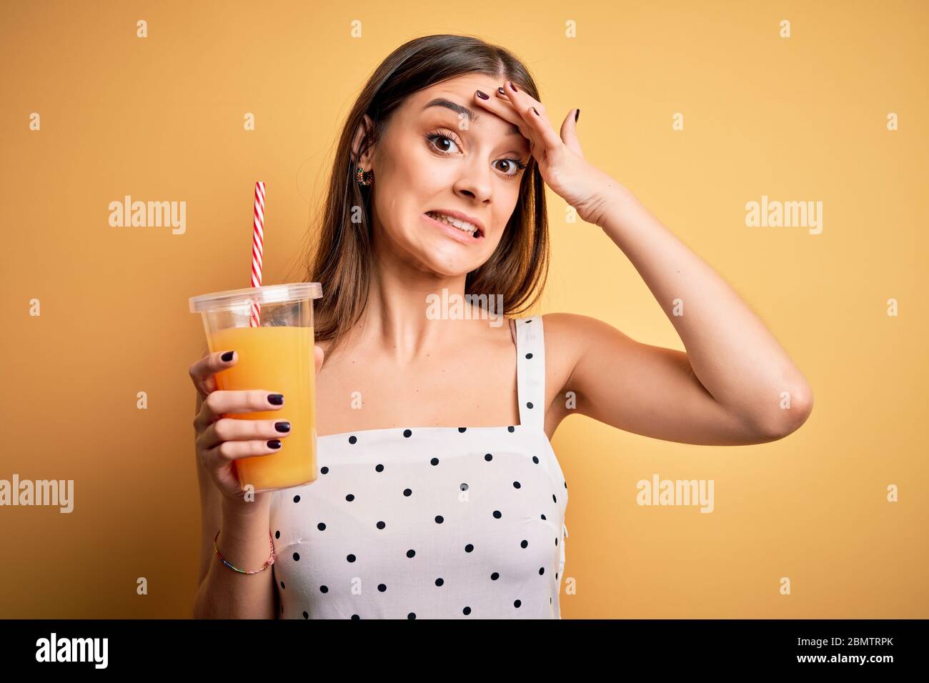 Young beautiful brunette woman drinking healthy orange juice over ...