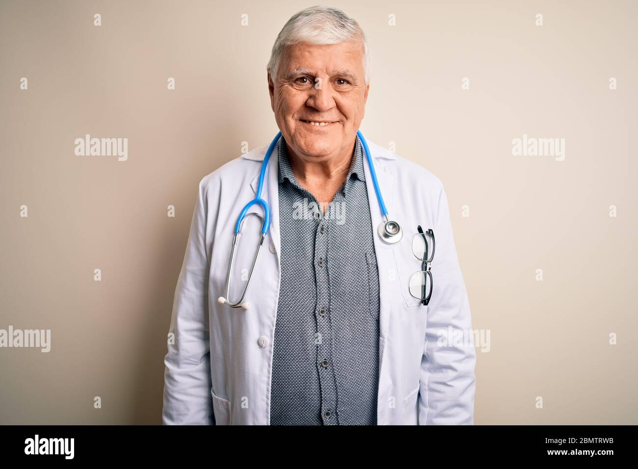 Senior handsome hoary doctor man wearing coat and stethoscope over ...
