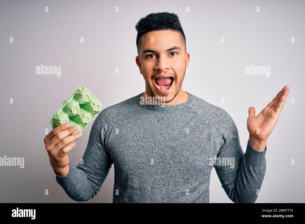 Young handsome man holding carton box of healthy fresh eggs over white ...