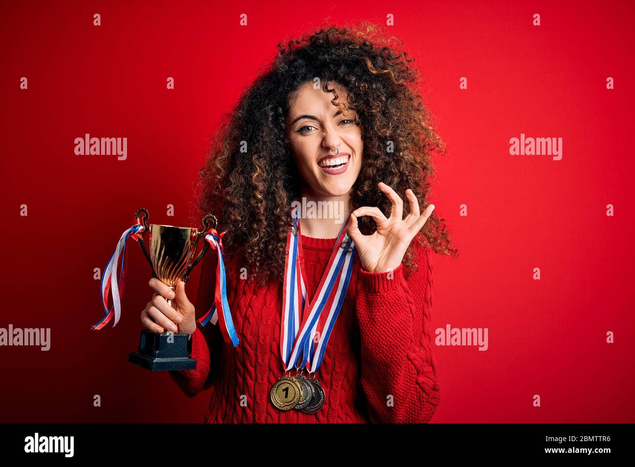 Young beautiful successful woman with curly hair and piercing holding ...