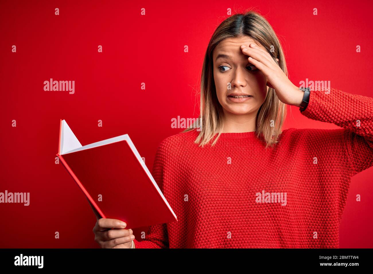Young beautiful woman reading book standing over isolated red ...