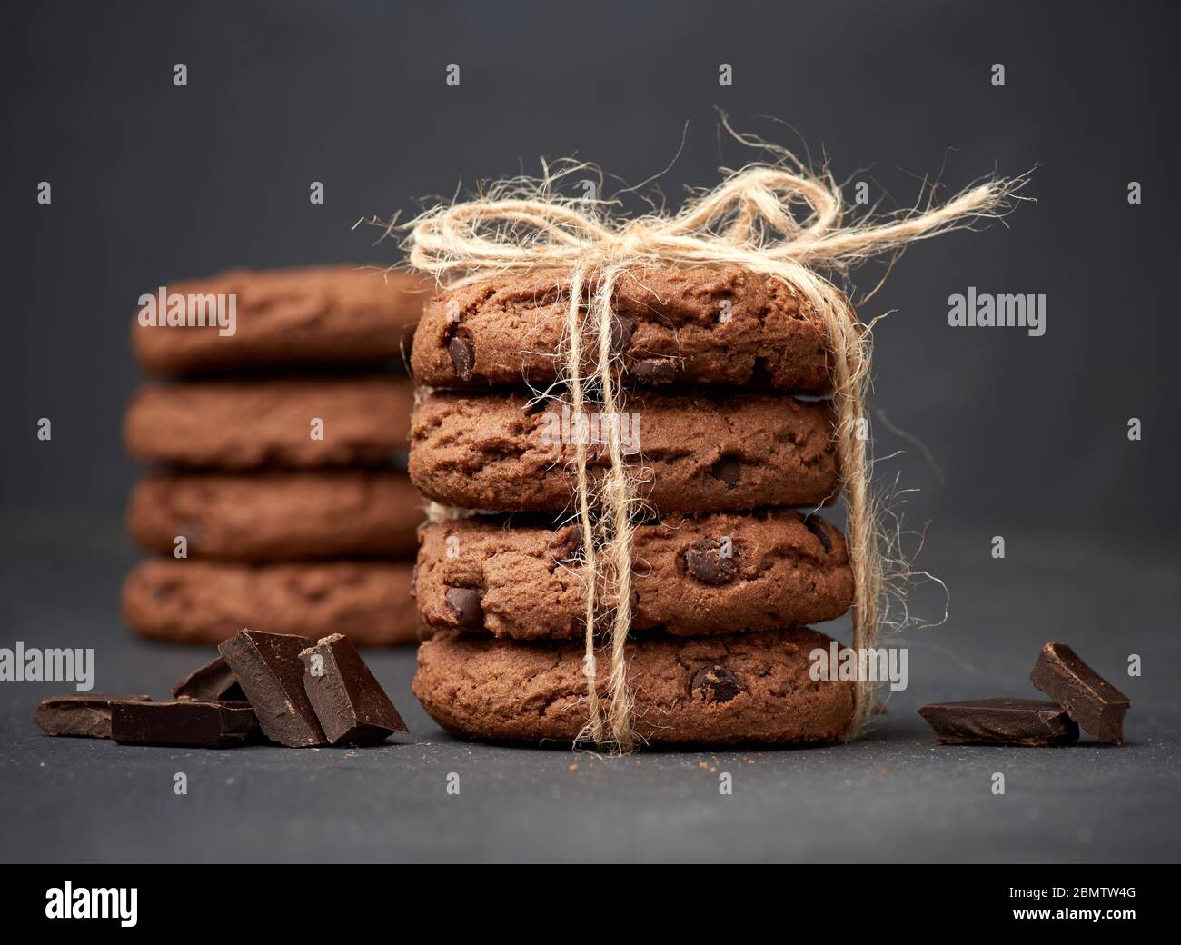 stack of round chocolate chip cookies tied with a rope on a black board ...