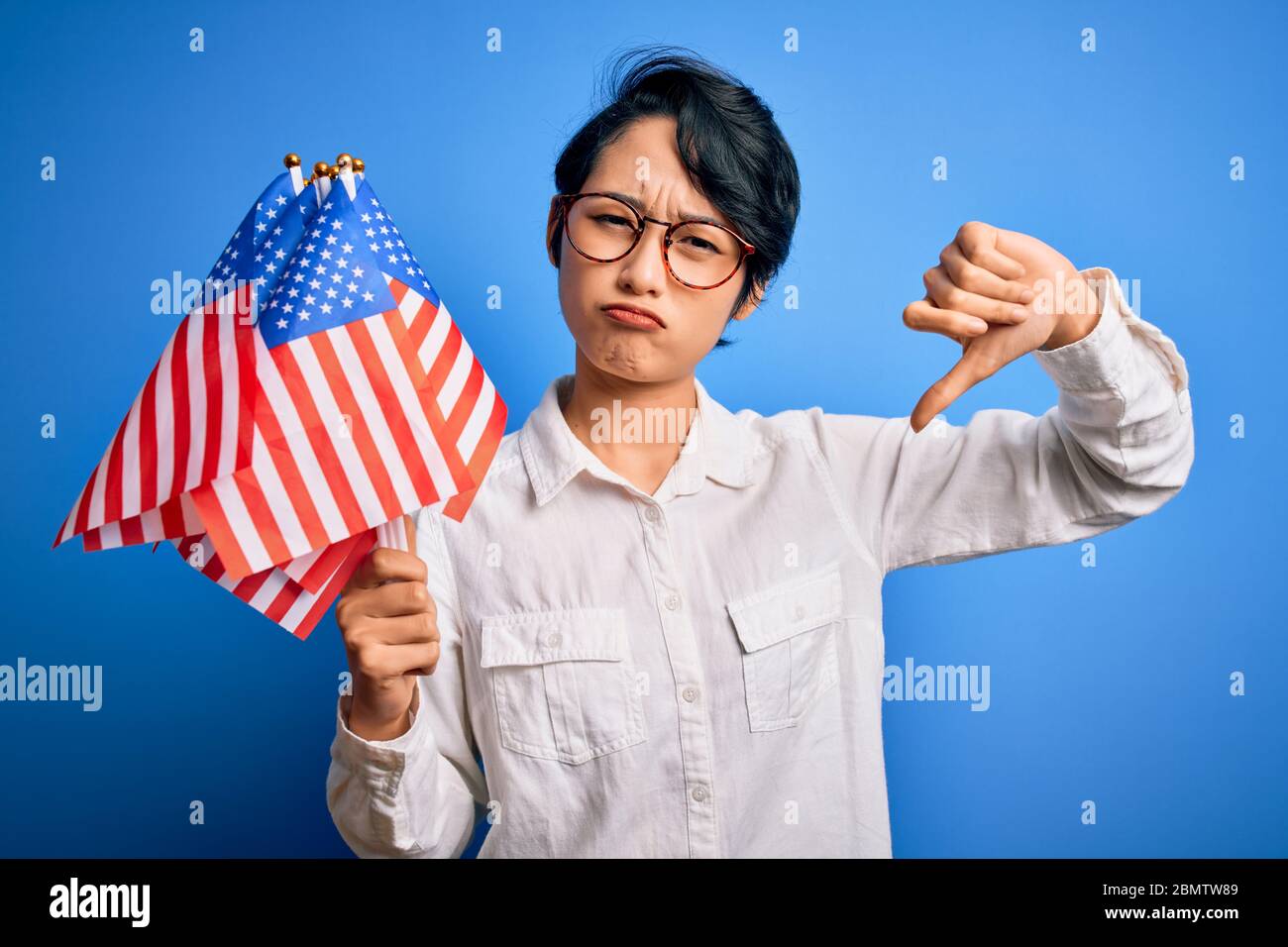 Young beautiful asian patriotic girl holding united states flags ...