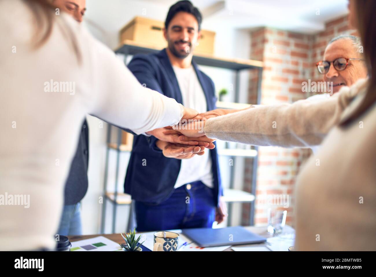Group of business workers standing with hands together at the office ...