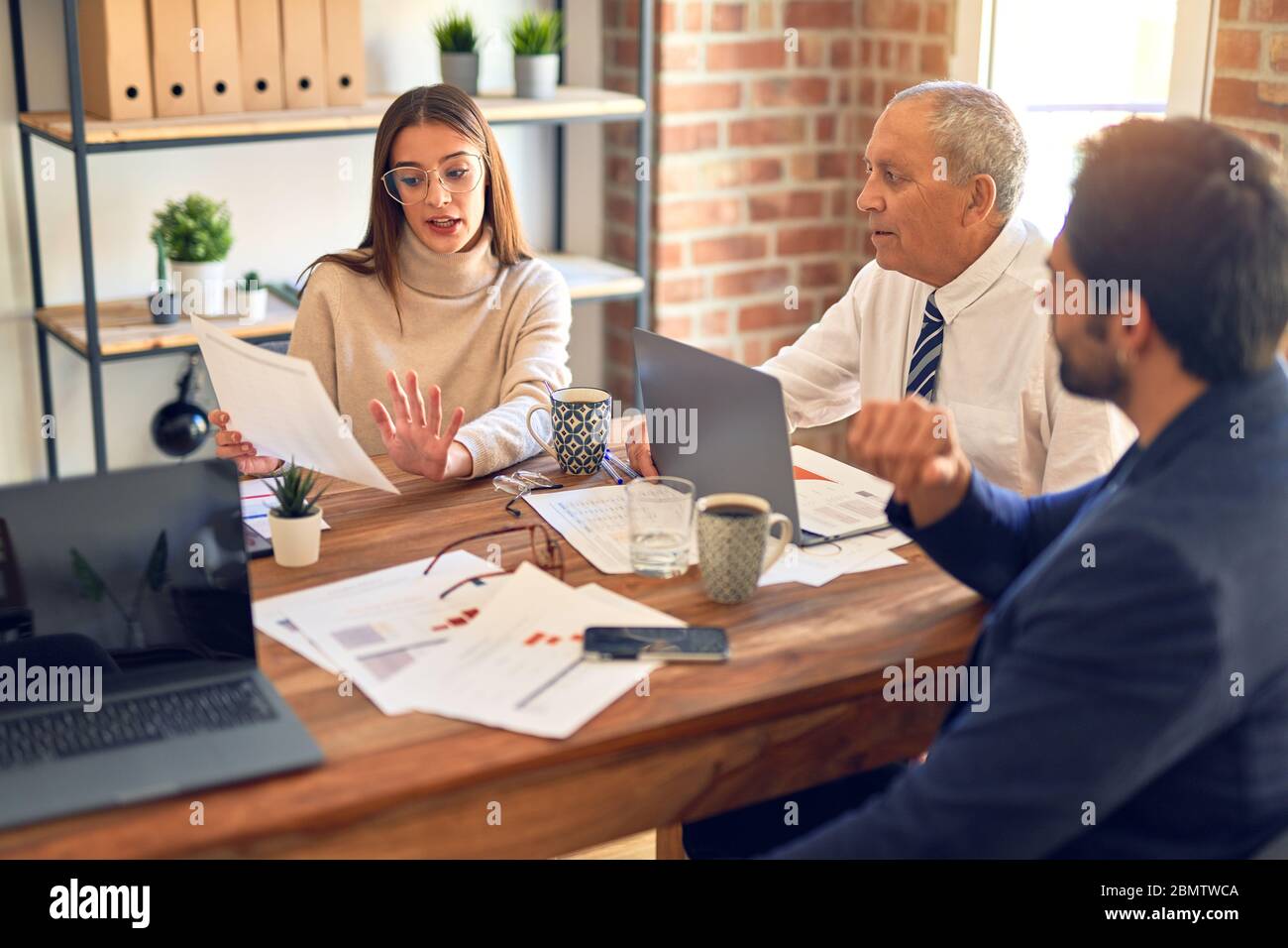 Group of business workers working together. Sitting on desk using ...
