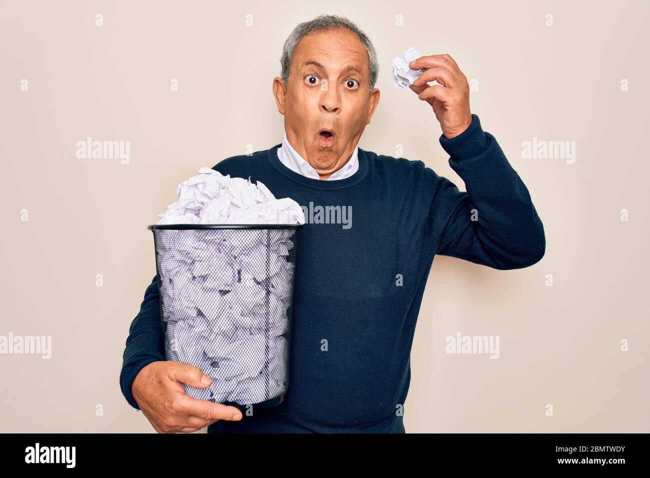 Senior grey-haired man holding full paper bin with crumpled papers over ...