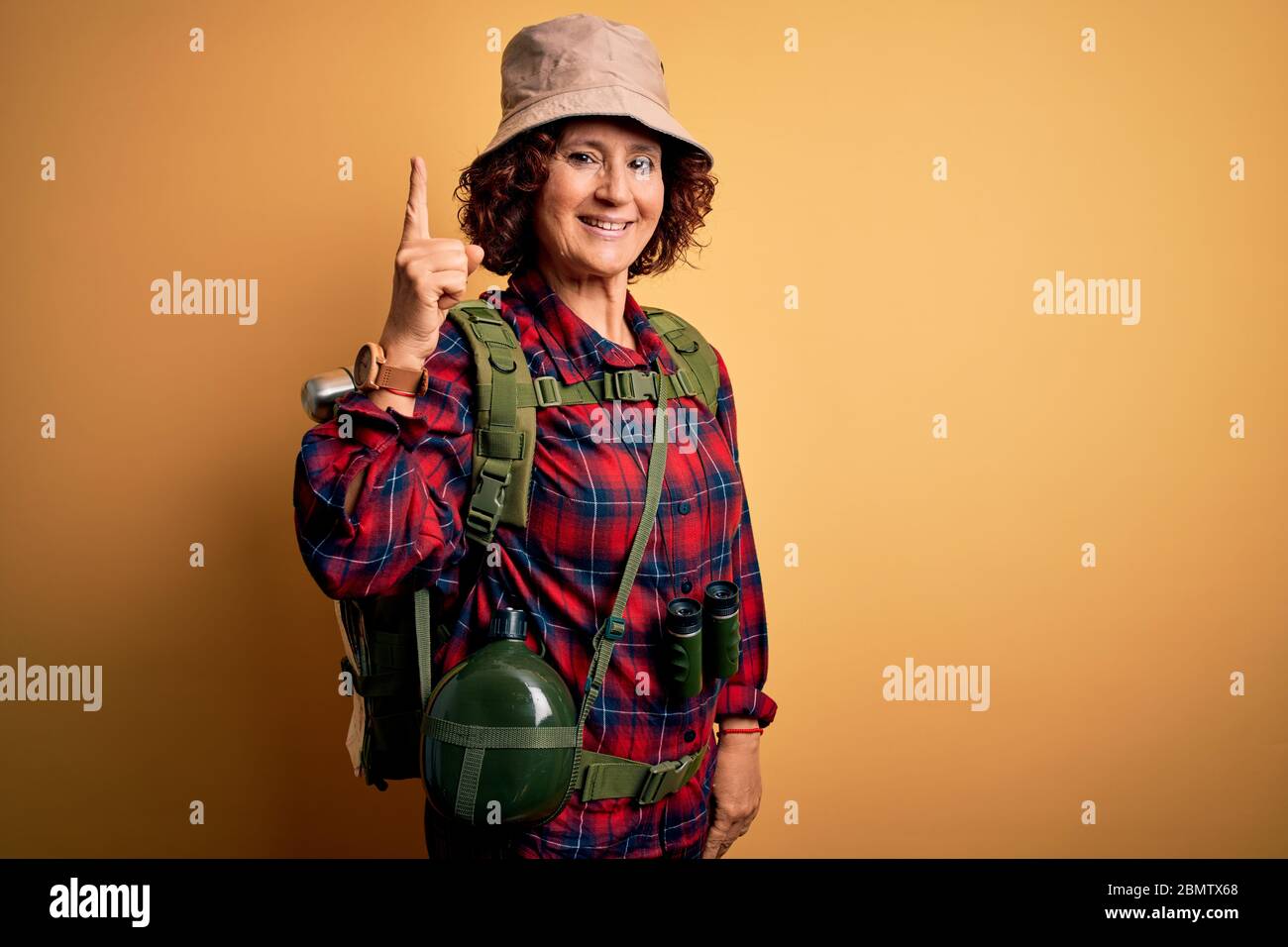 Middle age curly hair hiker woman hiking wearing backpack and water ...