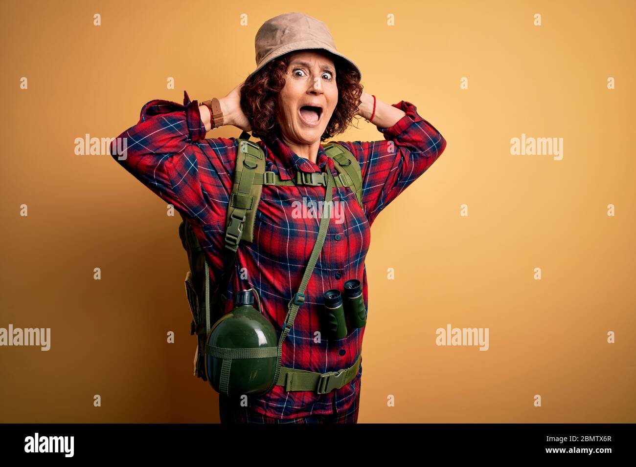 Middle age curly hair hiker woman hiking wearing backpack and water ...