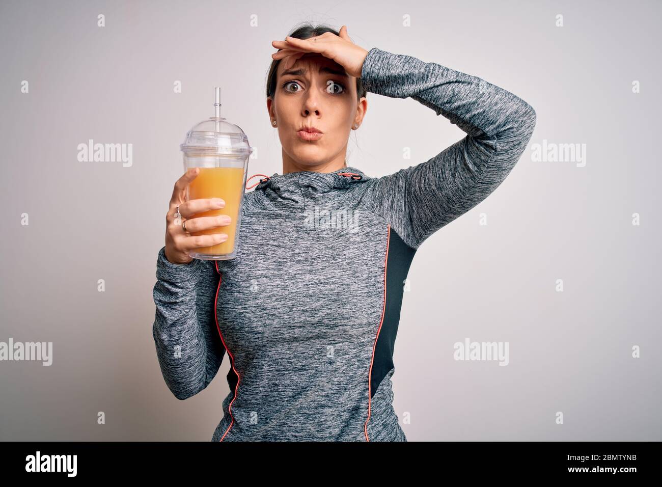 Young fitness woman wearing sport workout clothes drinking fresh orange ...