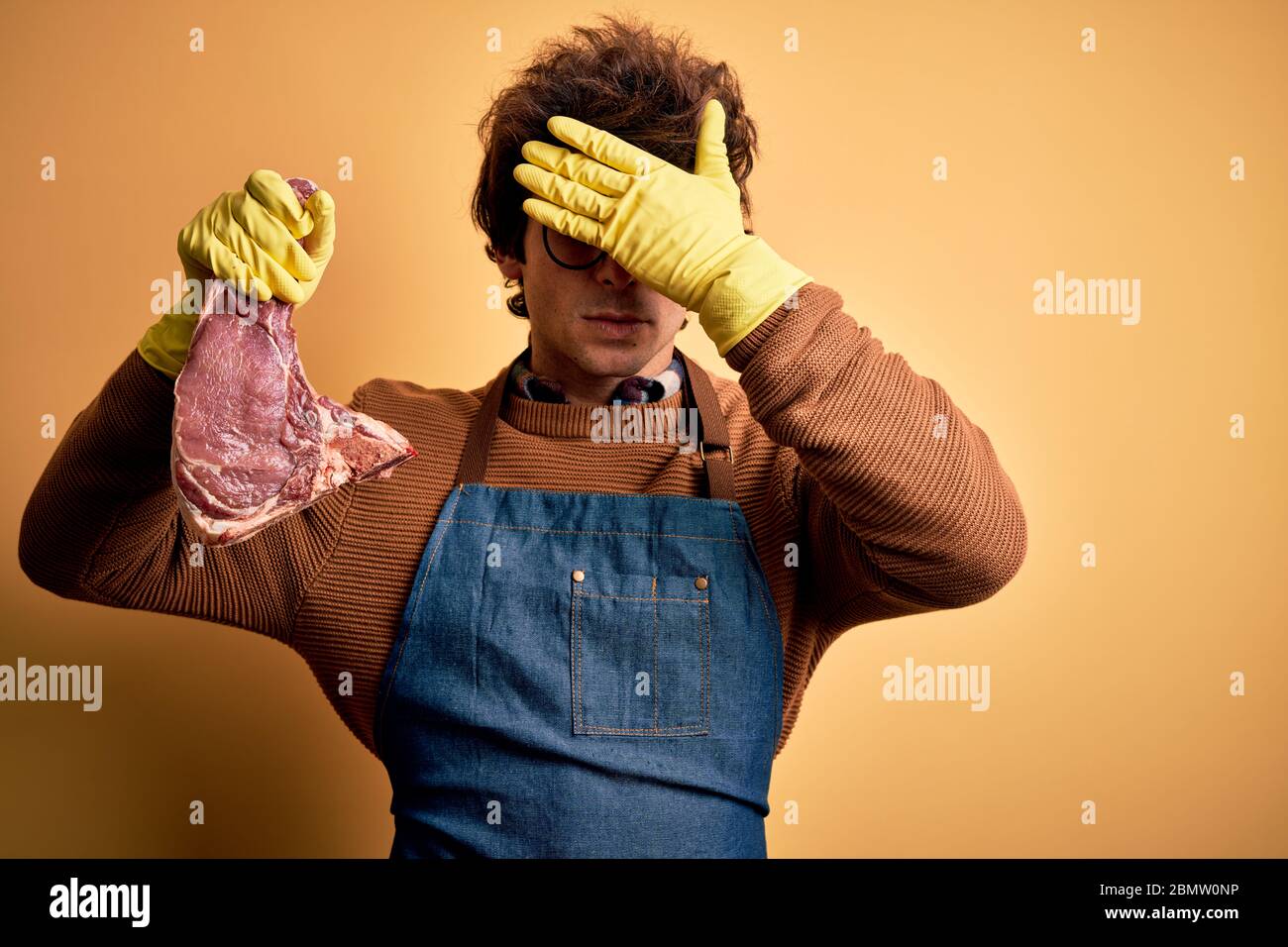 Young handsome butcher man holding meet steak standing over isolated ...