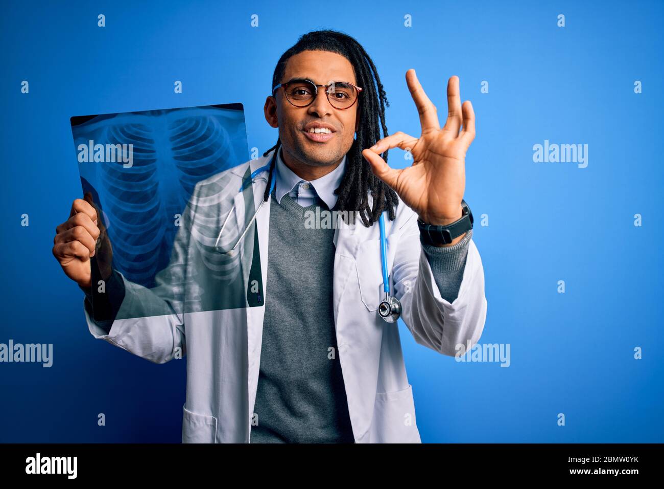 Young african american afro doctor man with dreadlocks holding chest ...