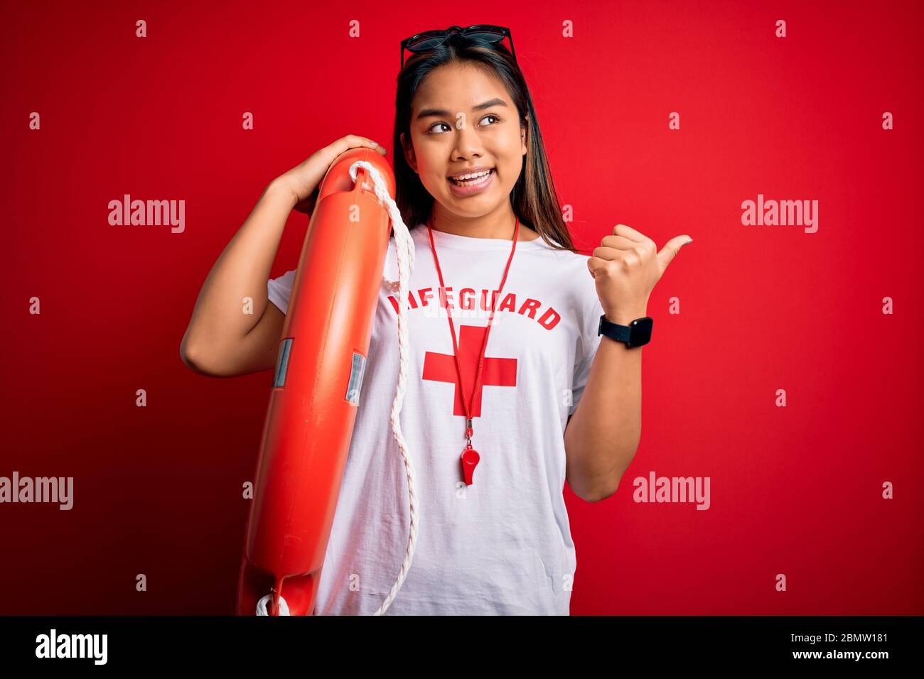 Young asian lifeguard girl wearing t-shirt with red cross using whistle ...
