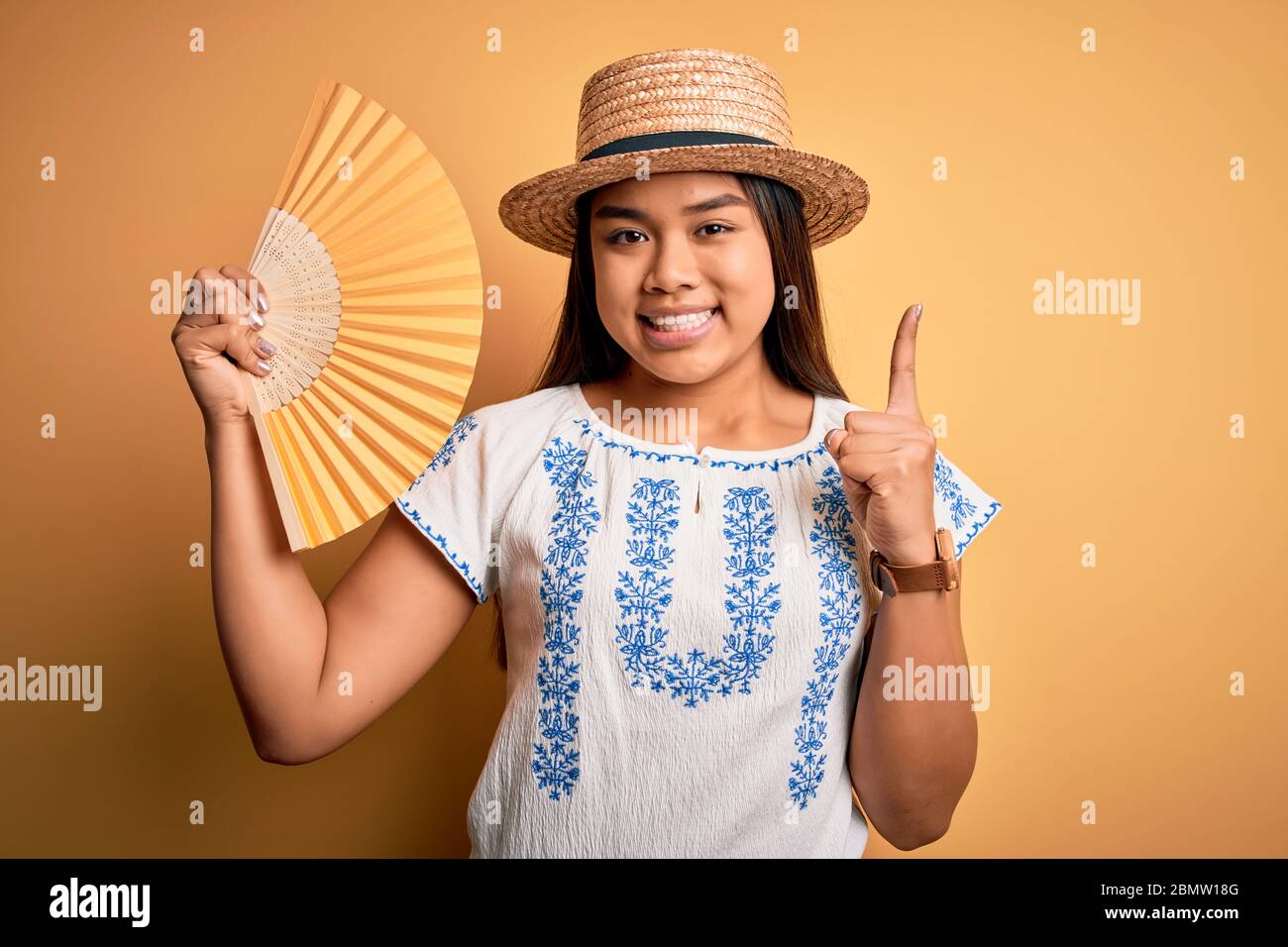 Young asian tourist girl on vacation wearing summer hat using hand fan ...