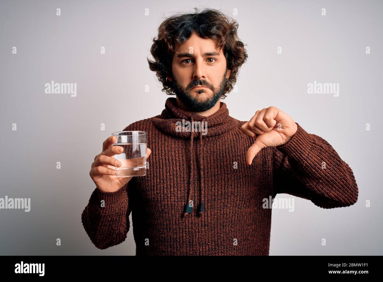 Young handsome man with beard drinking glass of water over isolated ...