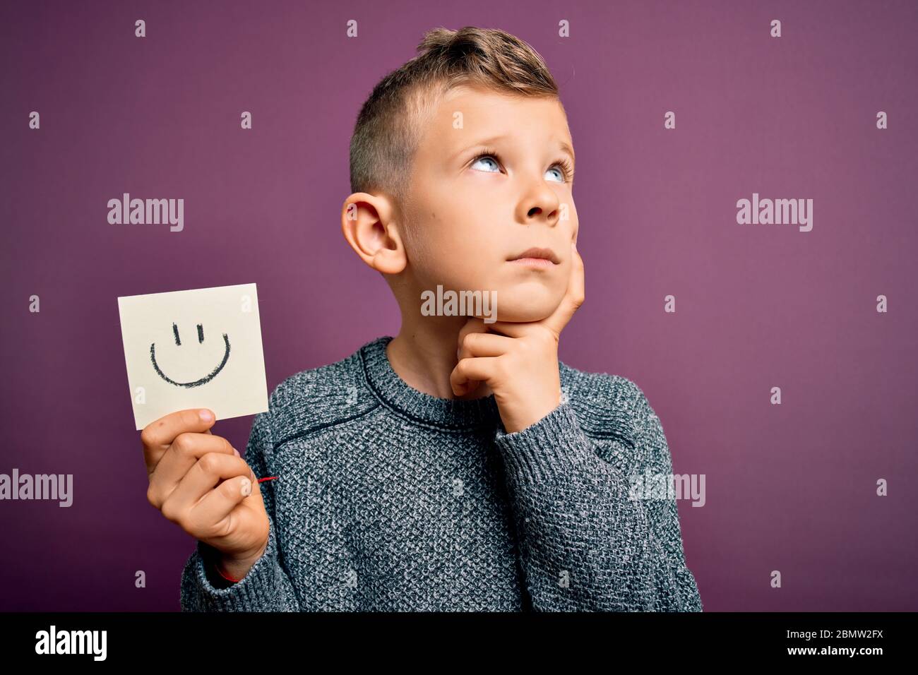 Young little caucasian kid showing smiley face on a paper note as happy ...