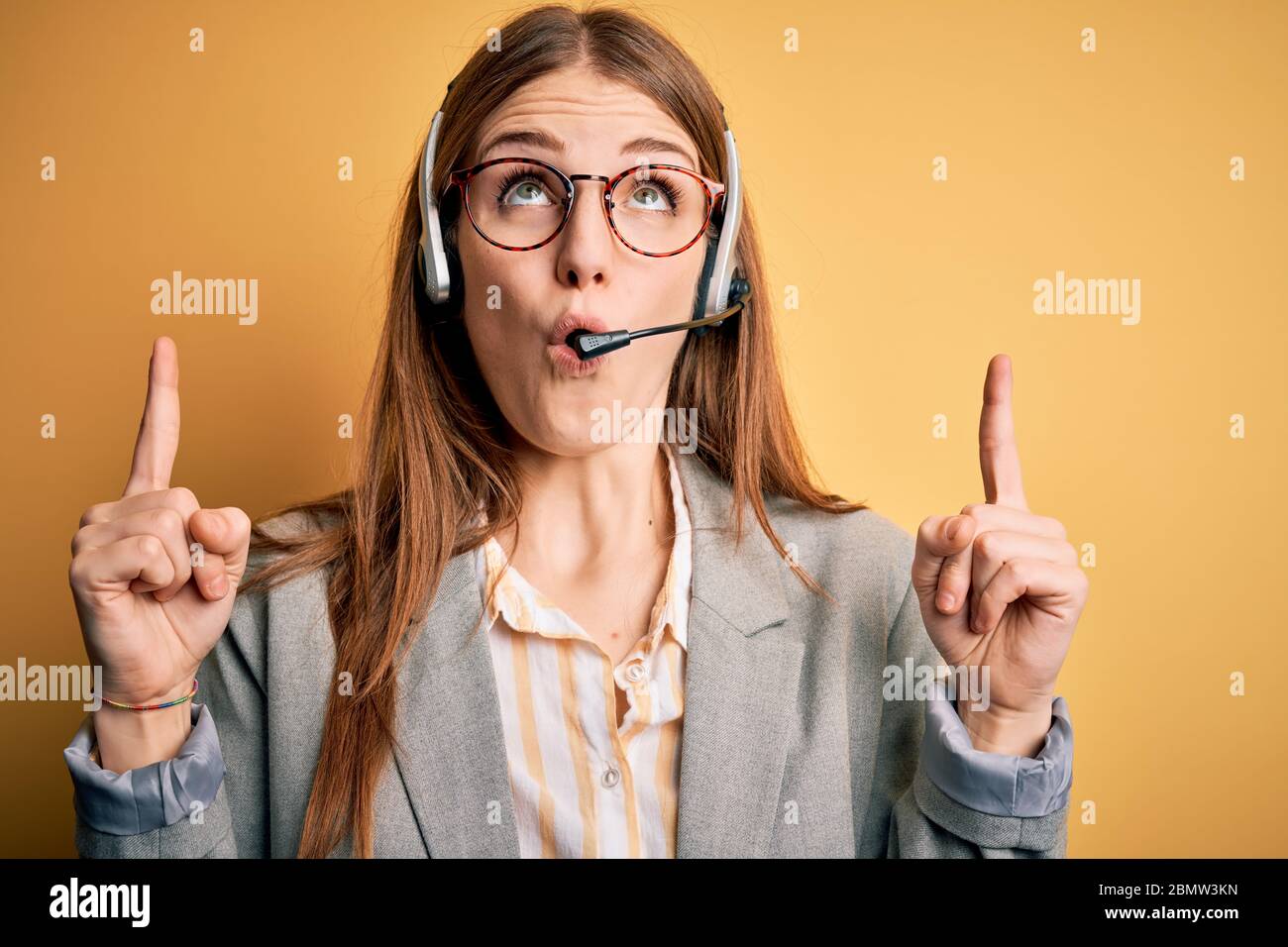 Young redhead call center agent woman overworked wearing glasses using ...