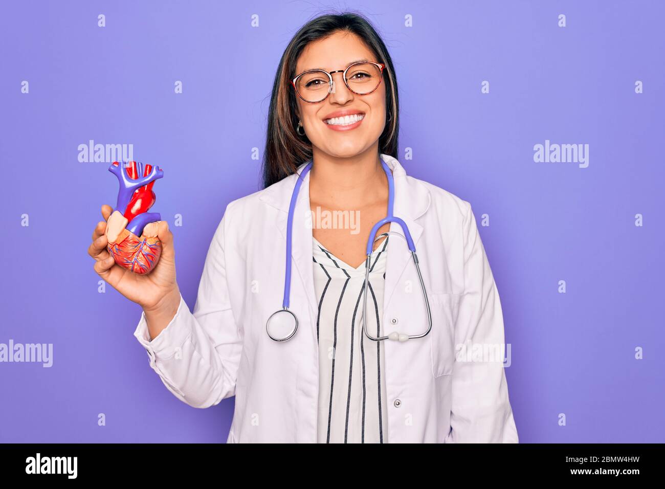 Young doctor cardiology specialist woman holding medical heart over ...