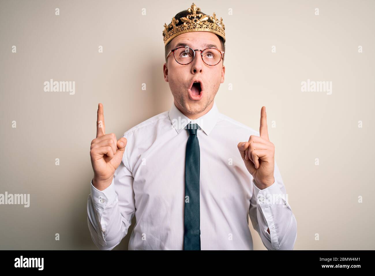 Young handsome caucasian business man wearing golden crown over ...