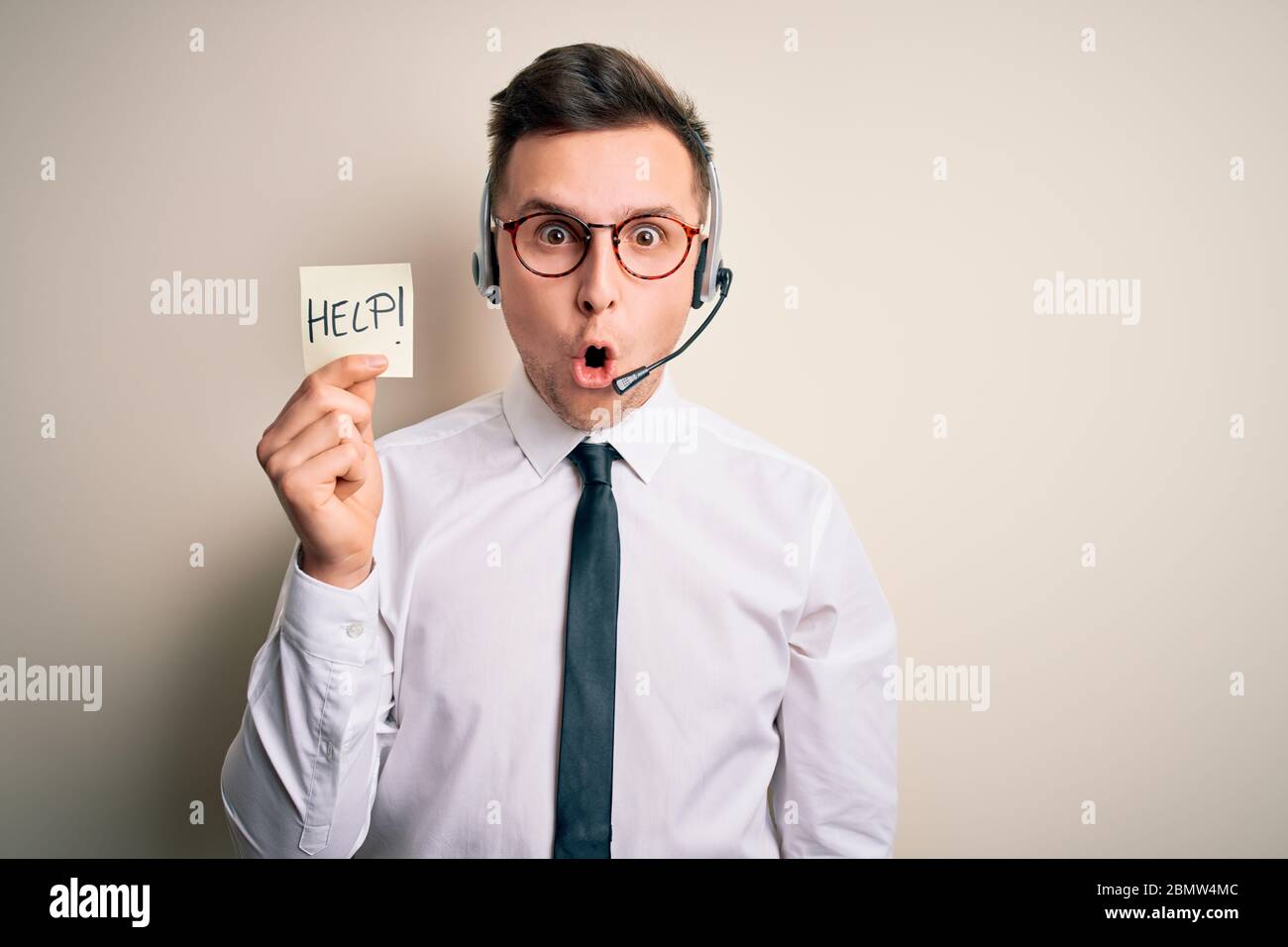 Young call center operator man wearing headset holding paper note with ...
