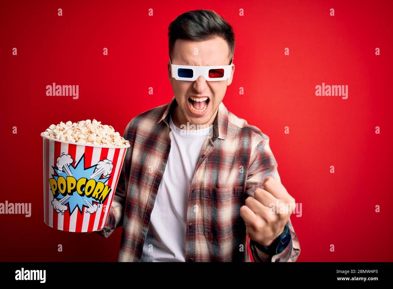 Young handsome caucasian man wearing 3d movie glasses and eating ...