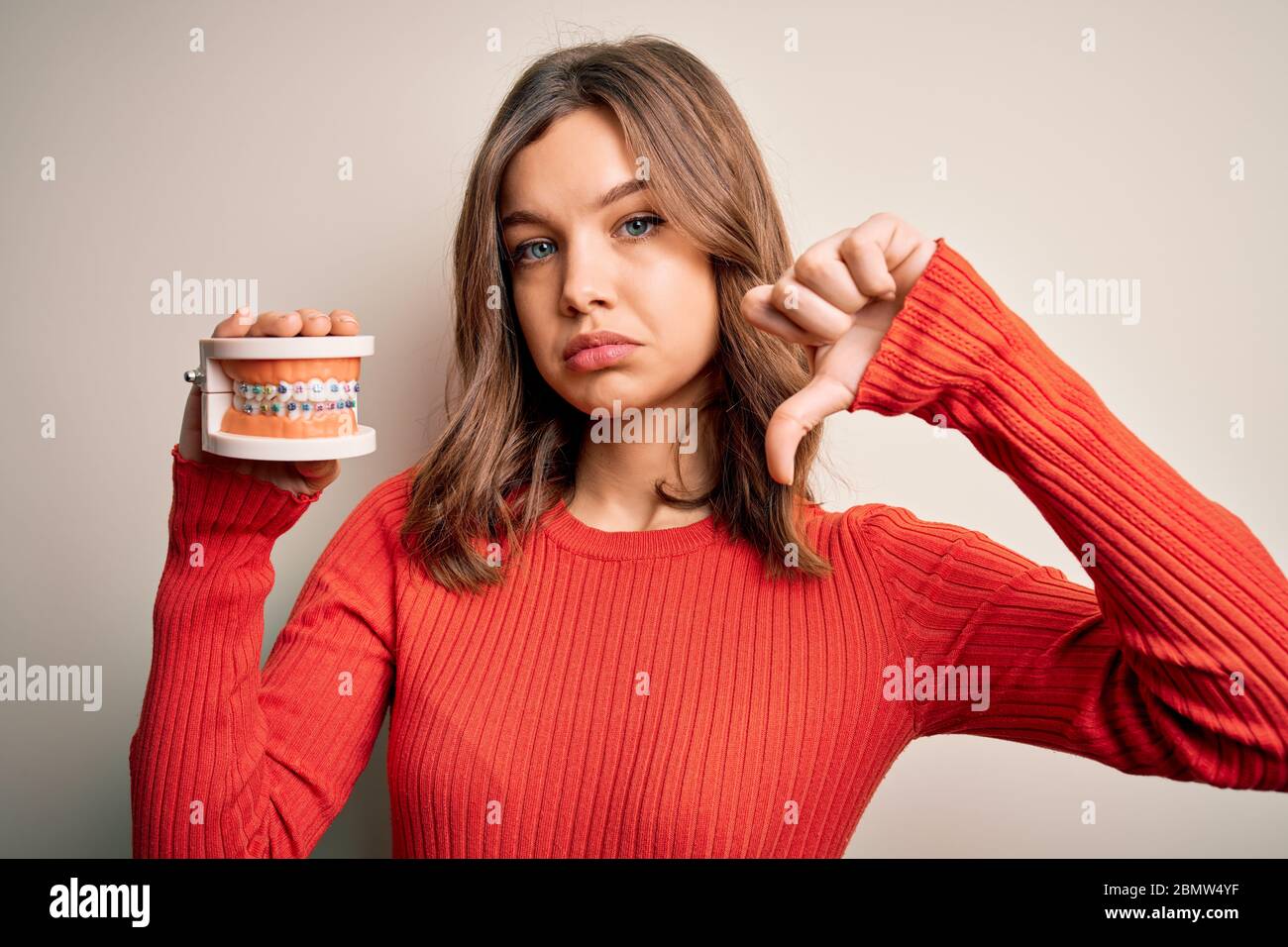 Young blonde girl holding orthodontist prosthesis denture over isolated ...