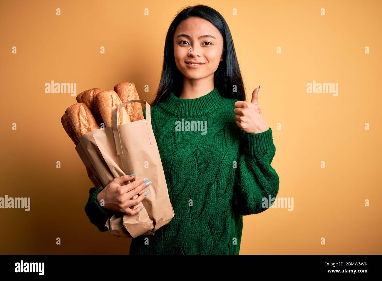 Young Beautiful Chinese Woman Holding Paper Bag With Bread Over