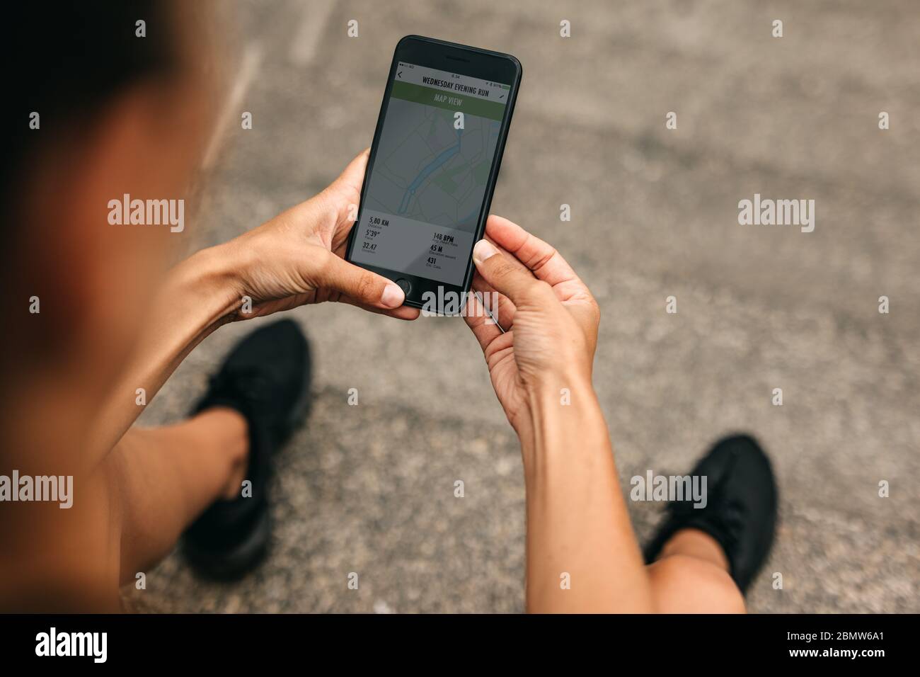 Over the shoulder view of a female runner using a fitness app on mobile ...