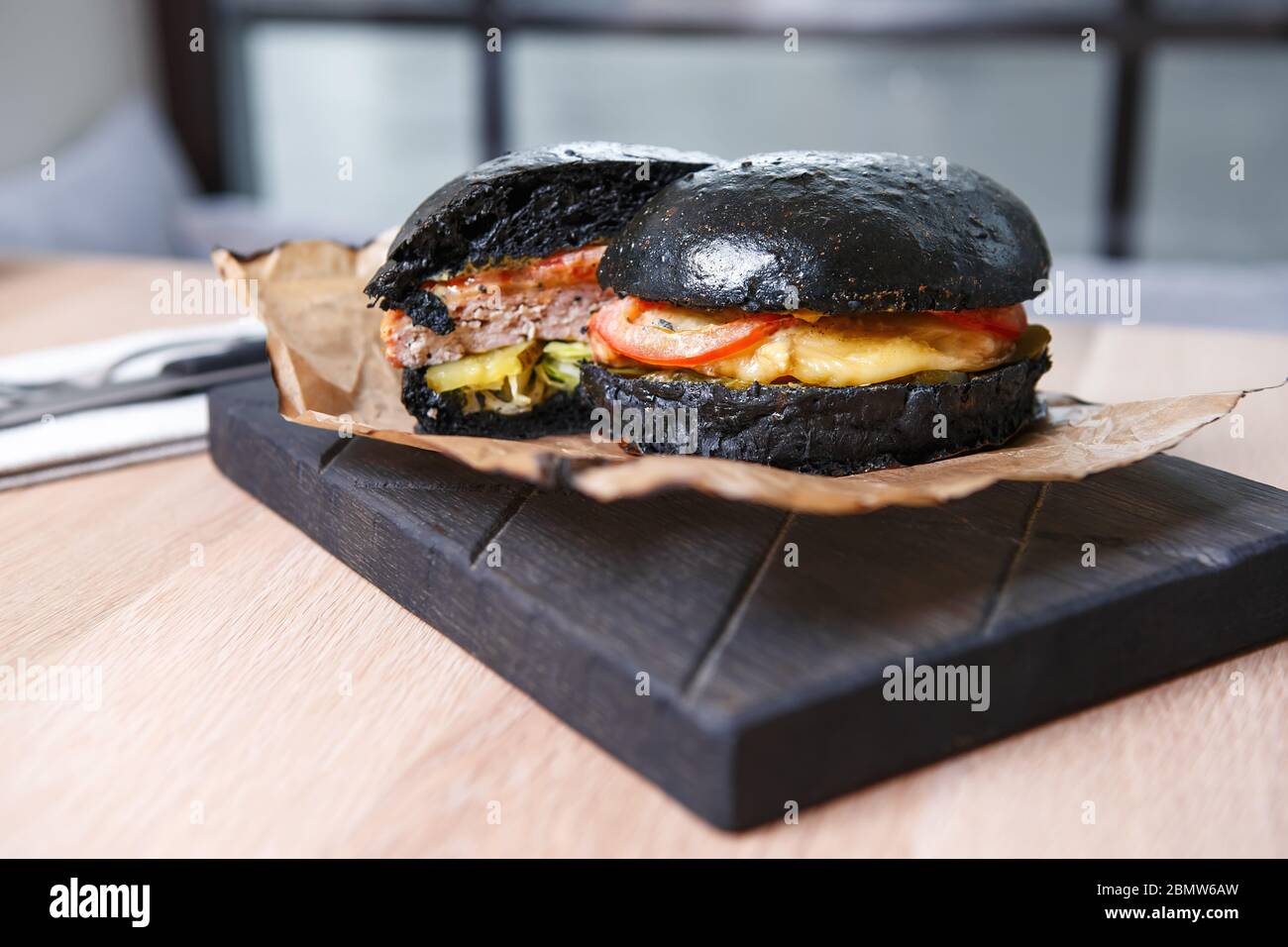 Black cheeseburger on wooden plate in restaurant.Delicious hamburger ...
