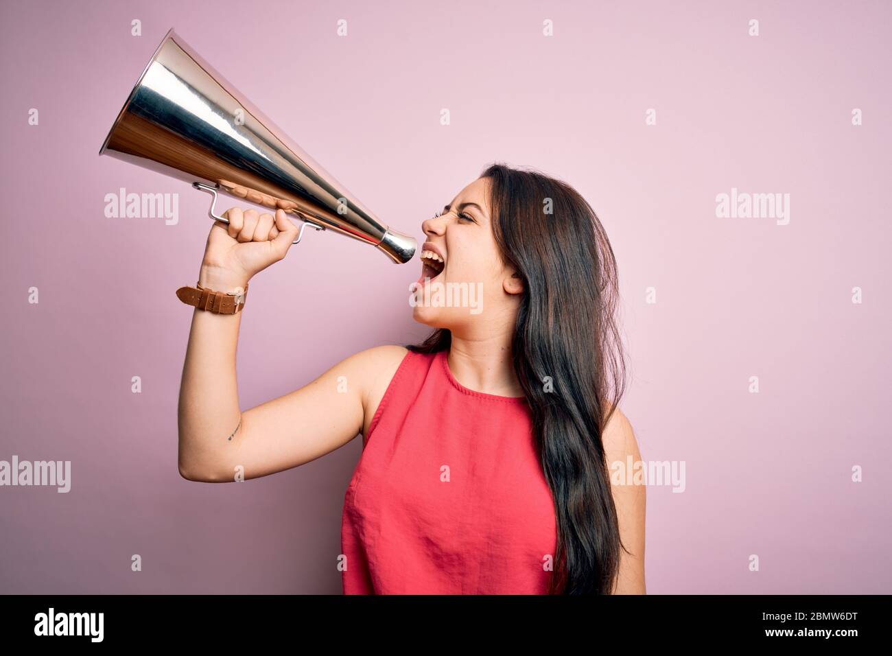 Young beautiful brunette speaker woman screaming communicate using ...