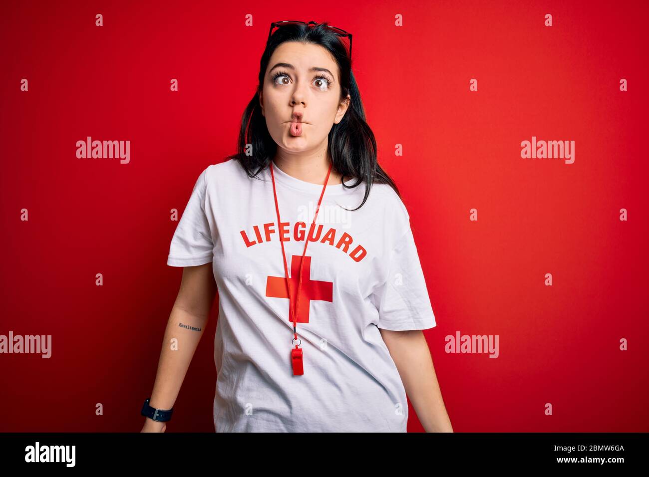 Young lifeguard woman wearing secury guard equipent over red background ...