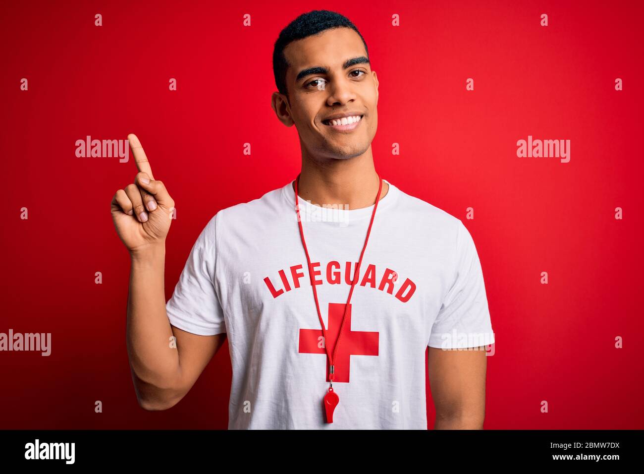 Young handsome african american lifeguard man wearing t-shirt with red ...