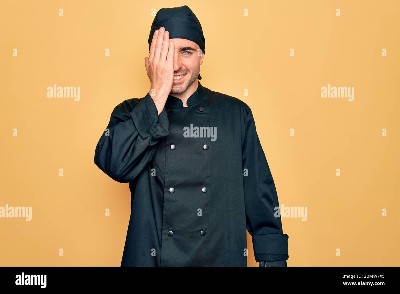 Young handsome cooker man with blue eyes wearing uniform and hat over ...