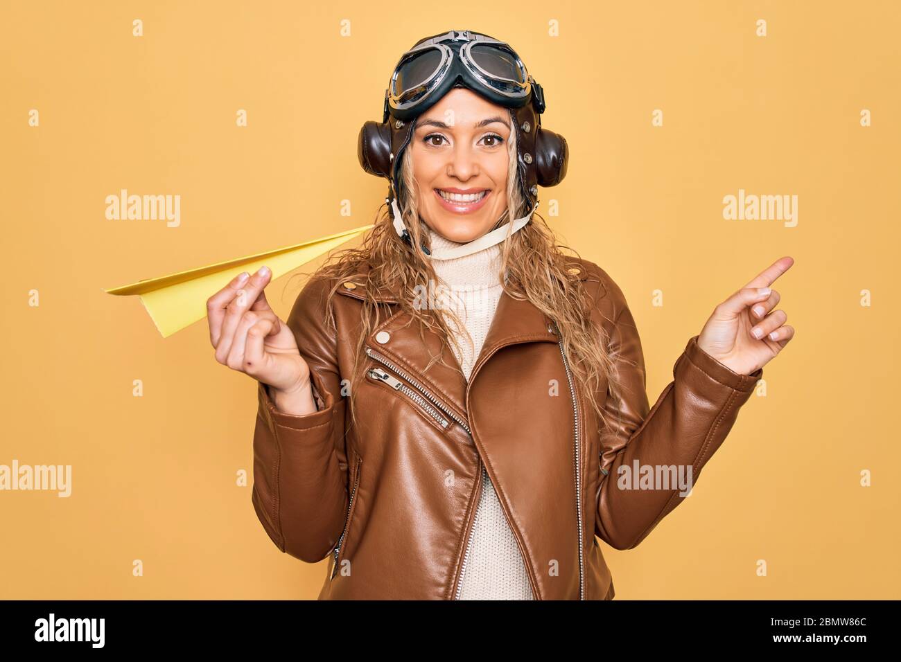 Beautiful blonde aviator woman wearing vintage pilot helmet whit ...