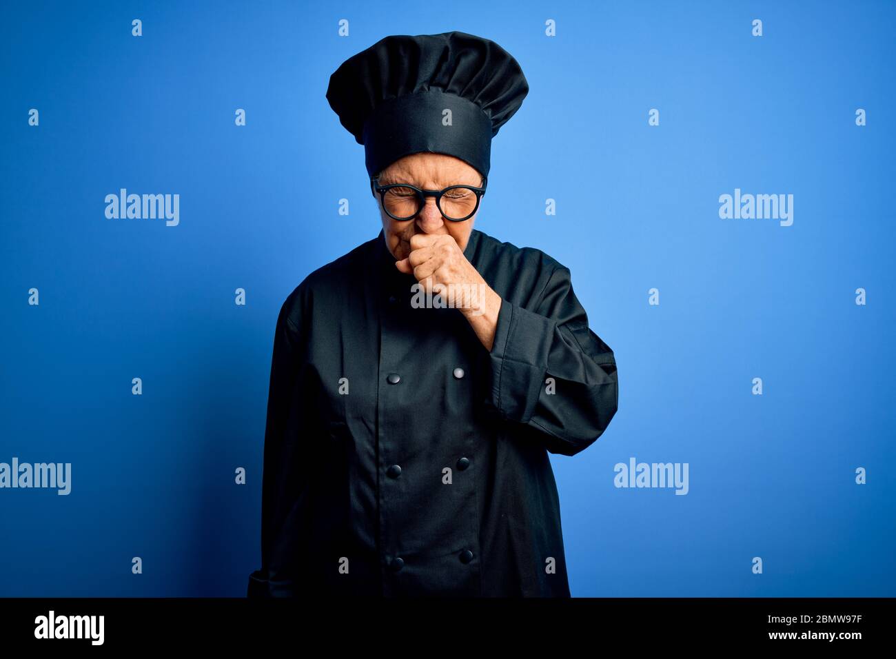 Senior beautiful grey-haired chef woman wearing cooker uniform and hat ...
