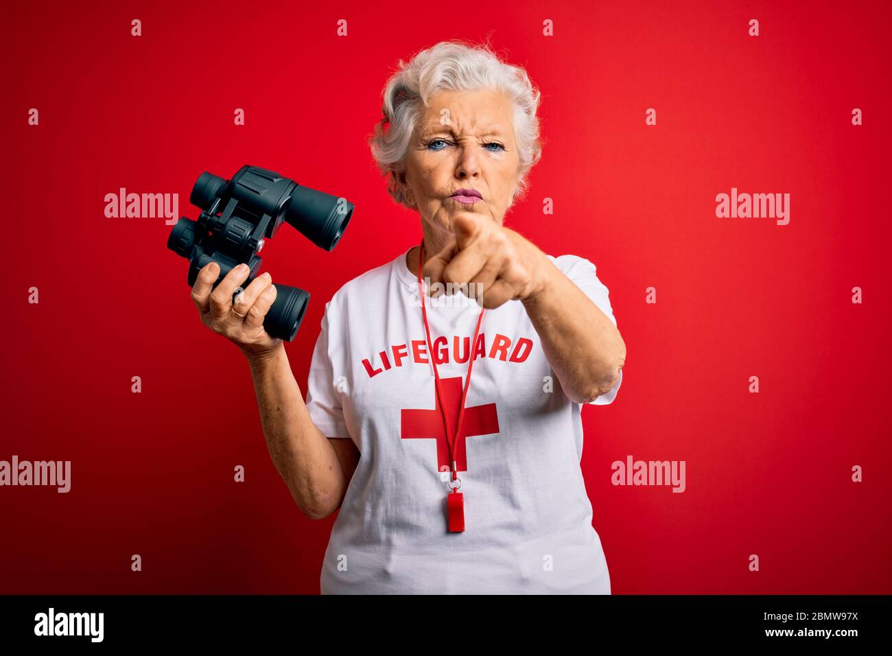 Senior beautiful grey-haired lifeguard woman using binoculars and ...