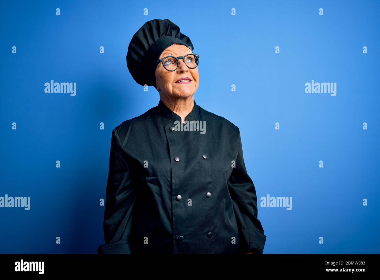 Senior beautiful grey-haired chef woman wearing cooker uniform and hat ...
