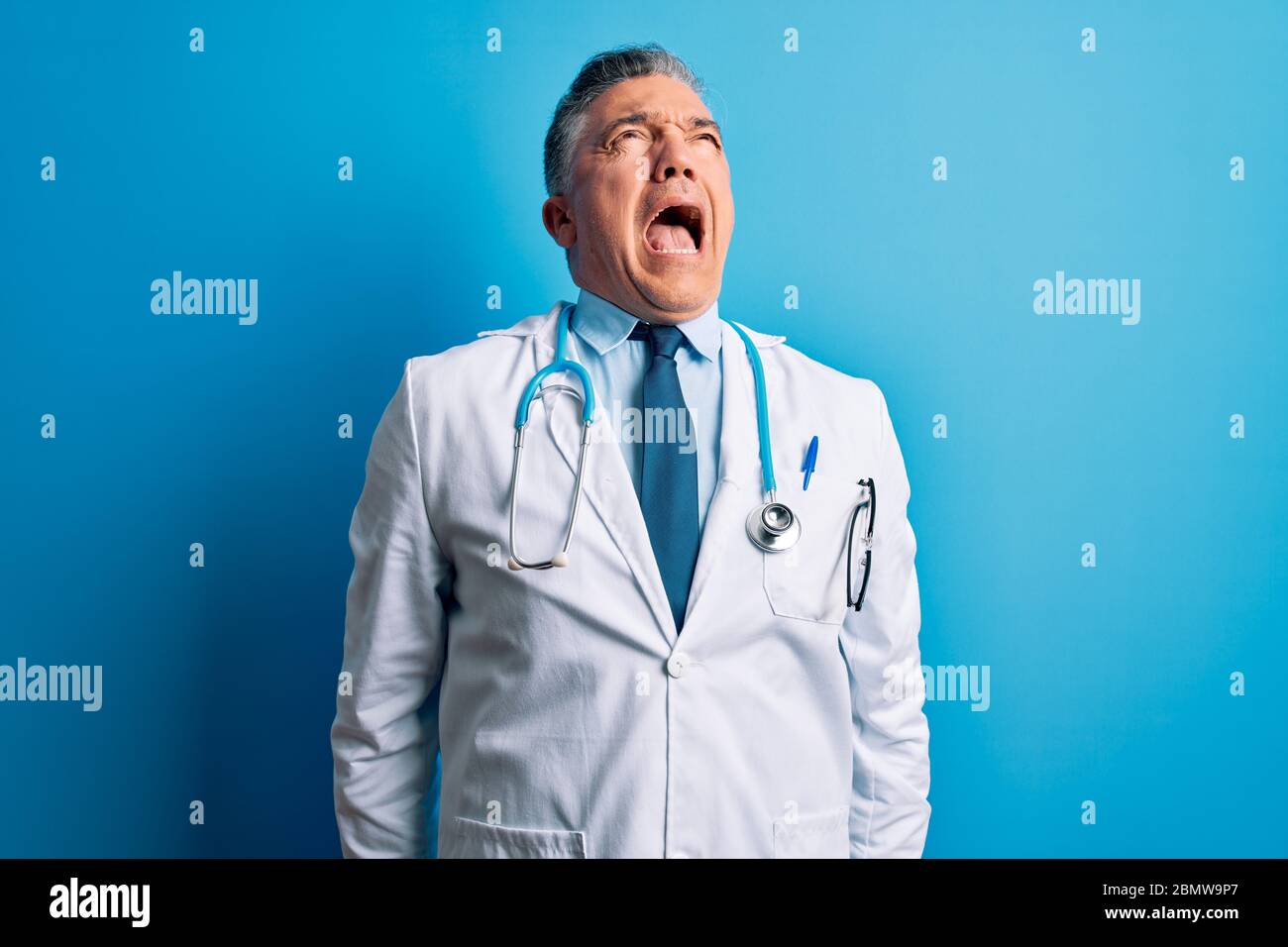Middle age handsome grey-haired doctor man wearing coat and blue ...