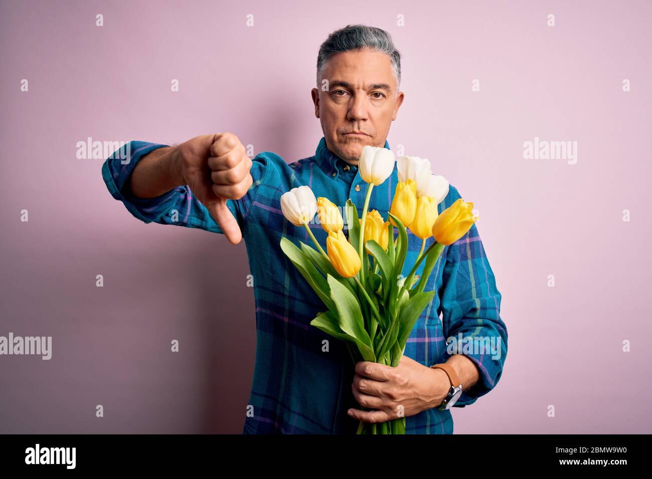 Middle age grey-haired man holding natural bouquet of yellow tulips ...
