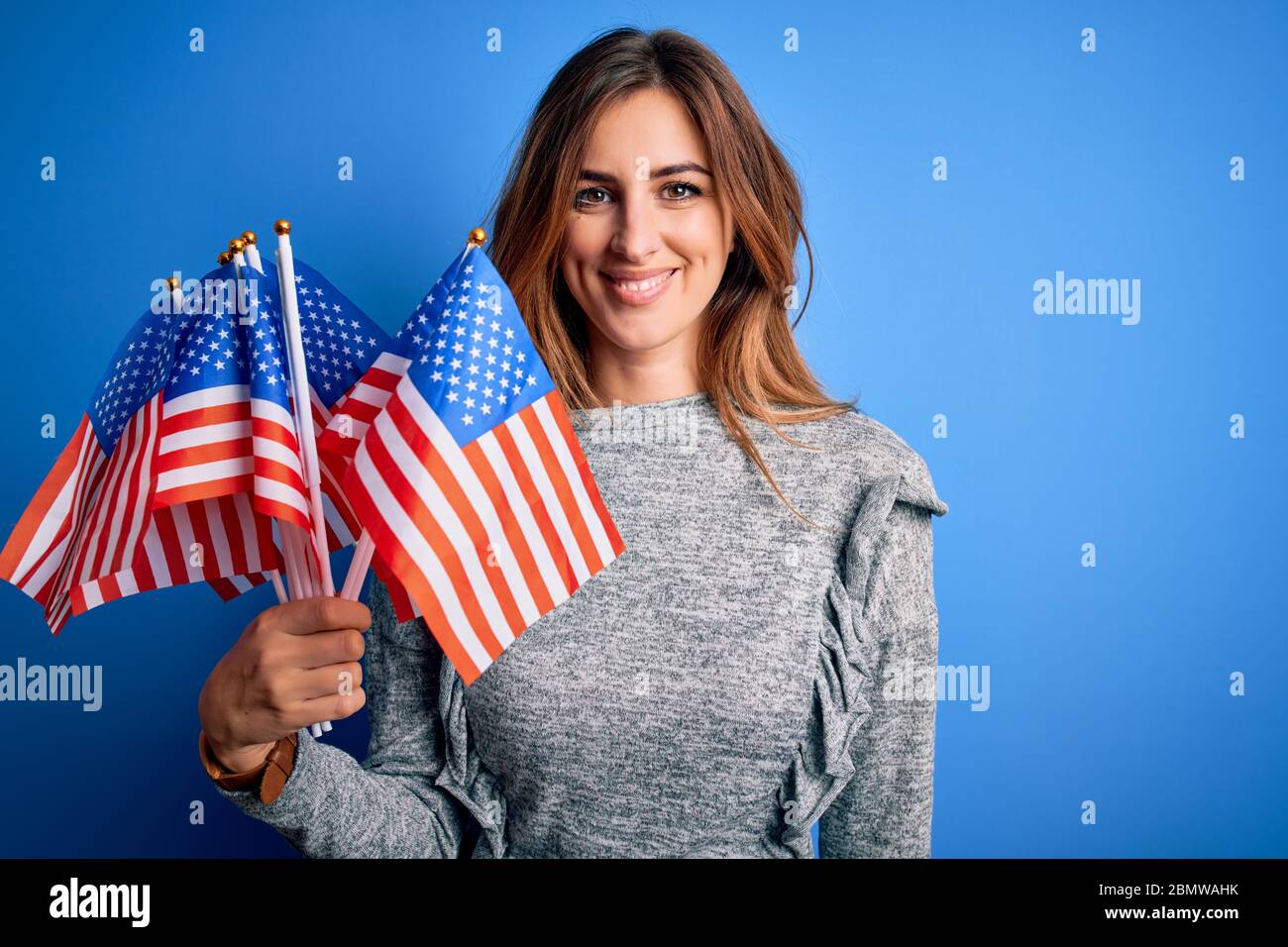 Young beautiful patriotic woman holding united states flags celebrating ...