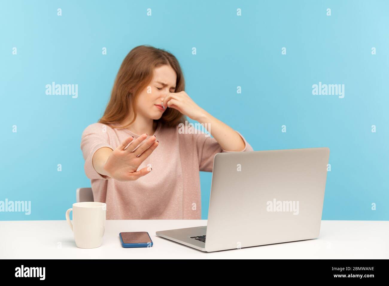 Bad smell. Confused young woman employee sitting at workplace with ...